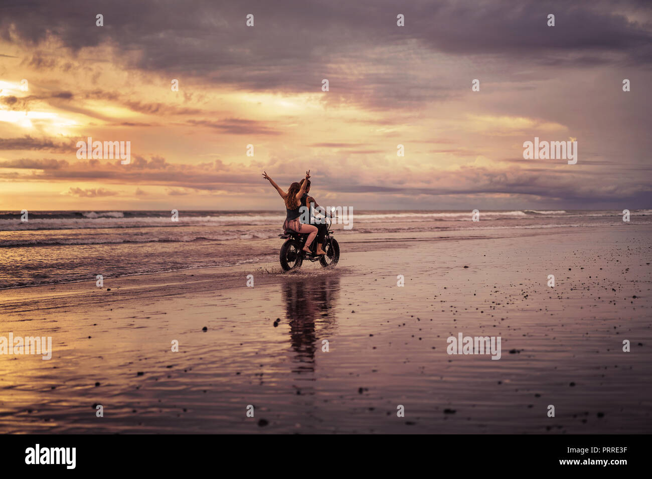 back view of happy couple riding motorcycle on ocean beach Stock Photo ...