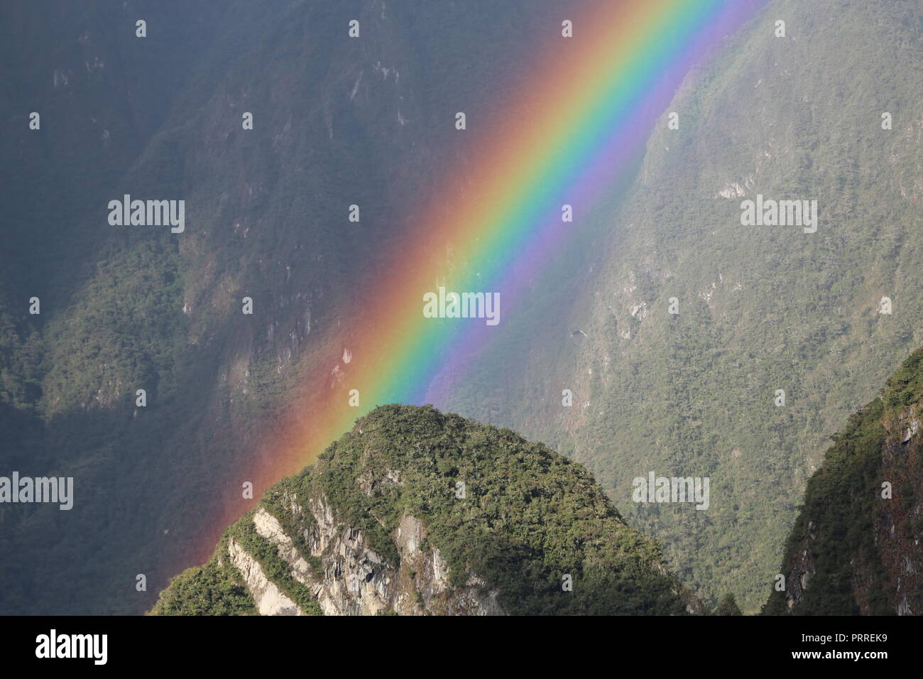 rainbow over mountain with shadow on one side and bright light on other ...