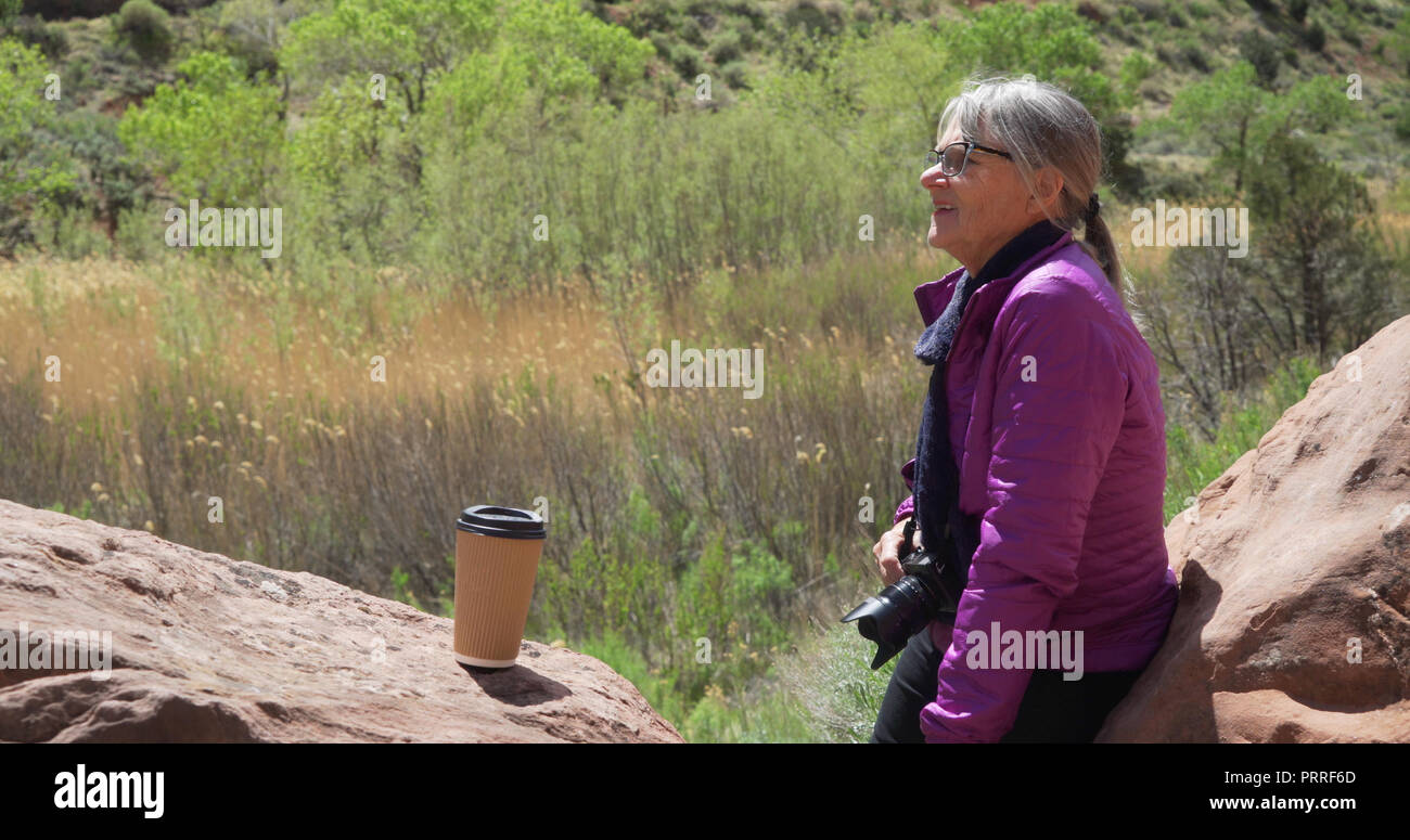 Mature nature loving woman using camera to take pictures of wildlife ...