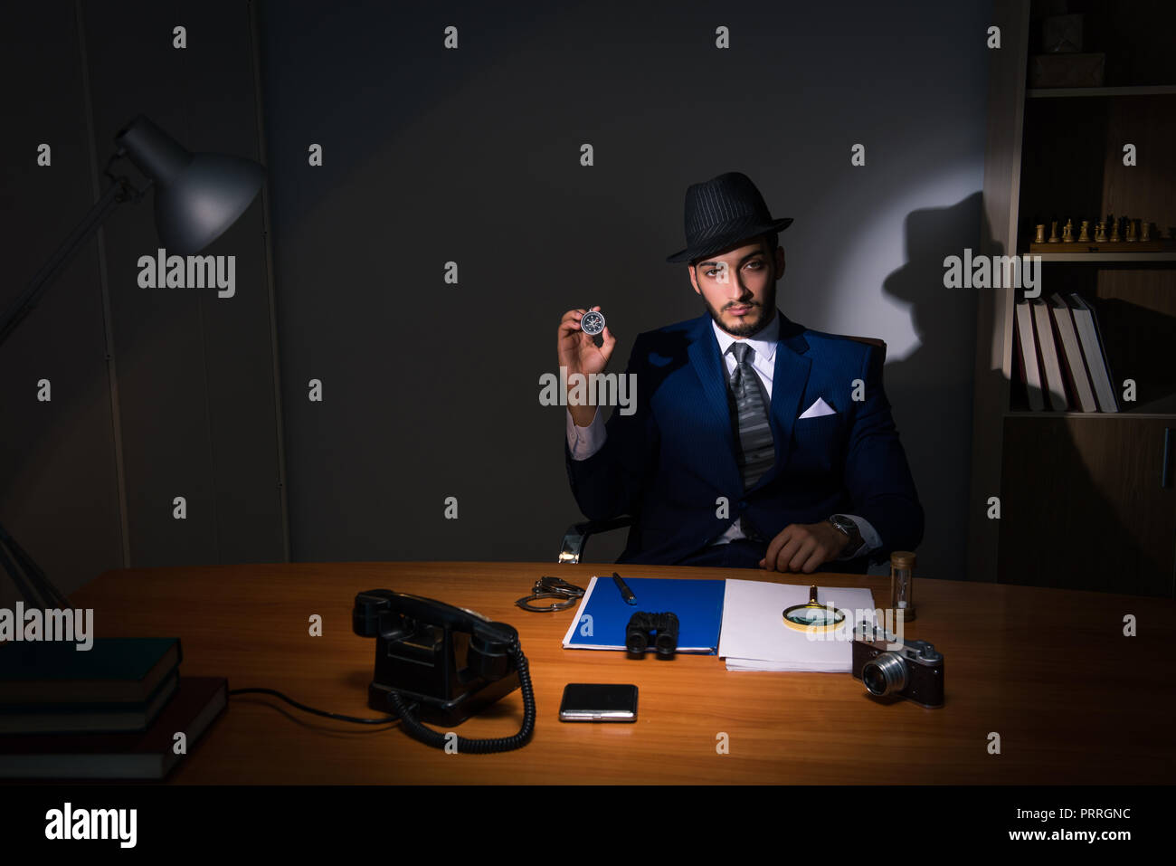 Detective sitting in dark room in vintage concept Stock Photo - Alamy