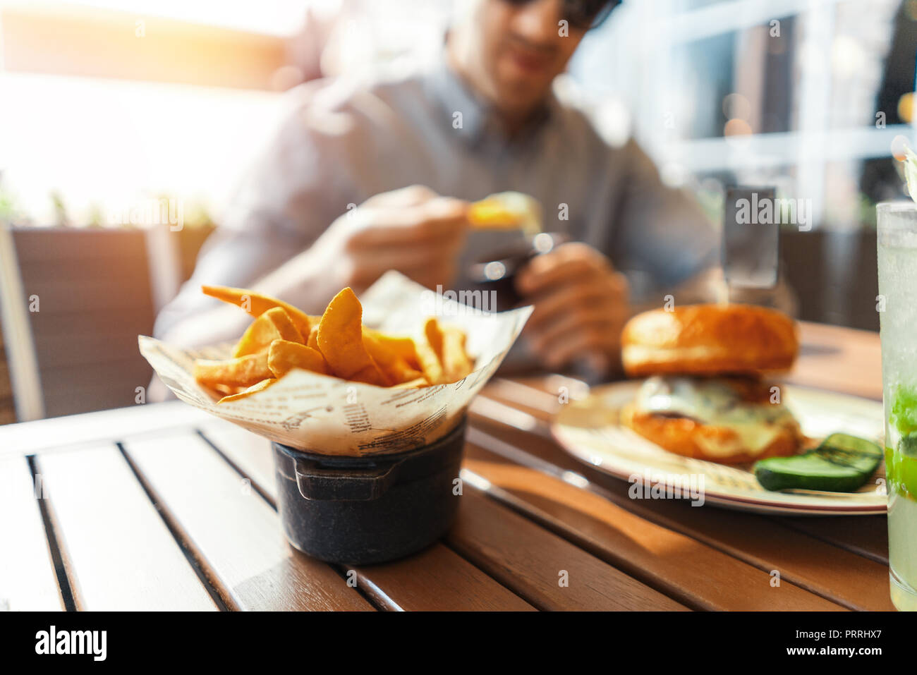 Close up of young attractive man eating french fries and burger at ...