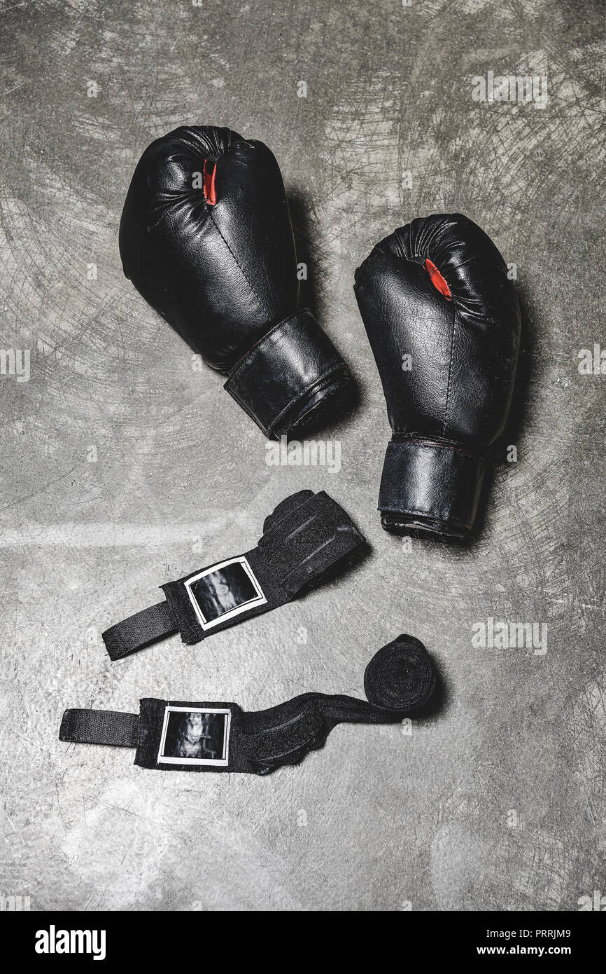 top view of boxing gloves with wrist wraps lying on concrete surface ...