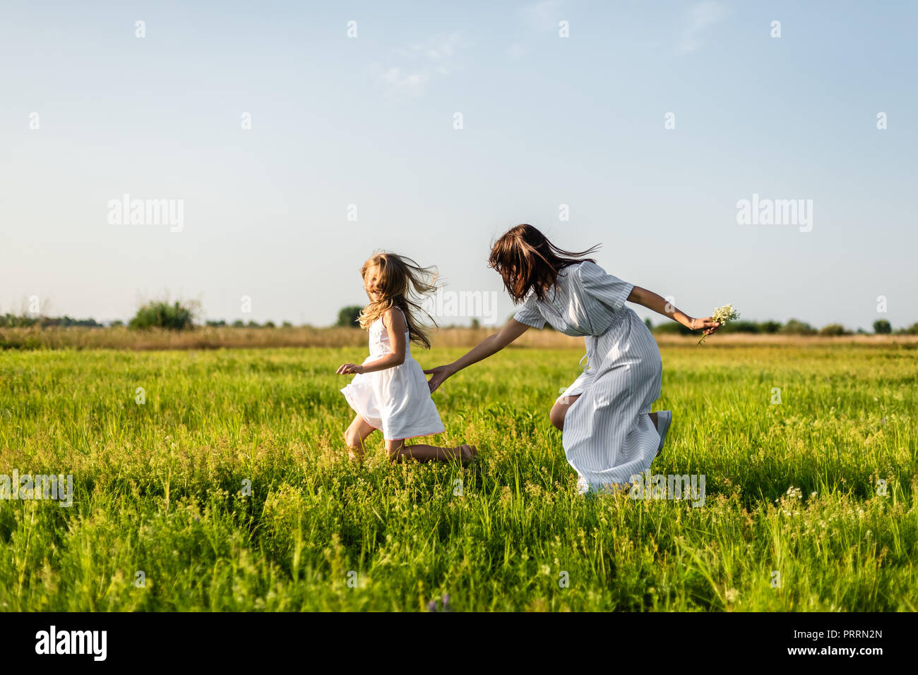 side view of mother and daughter running in green meadow together Stock ...