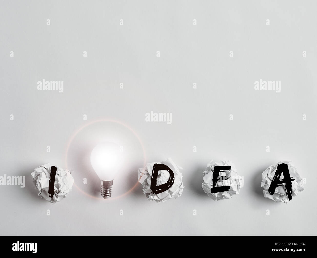 row of light bulb with crumpled papers and idea word on white surface ...
