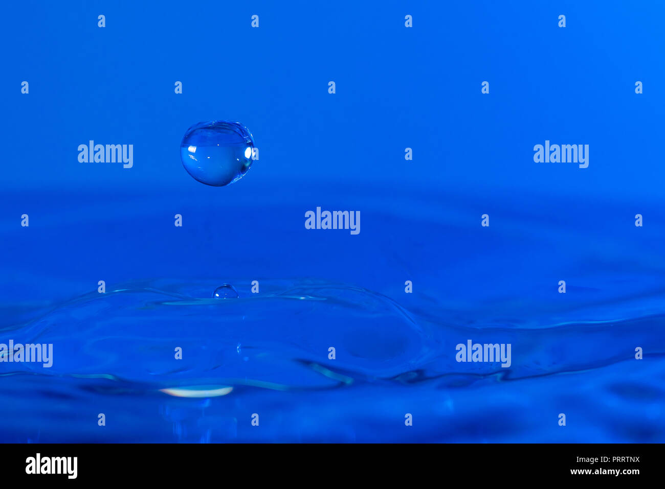 Colorful water droplet bouncing on water Stock Photo - Alamy