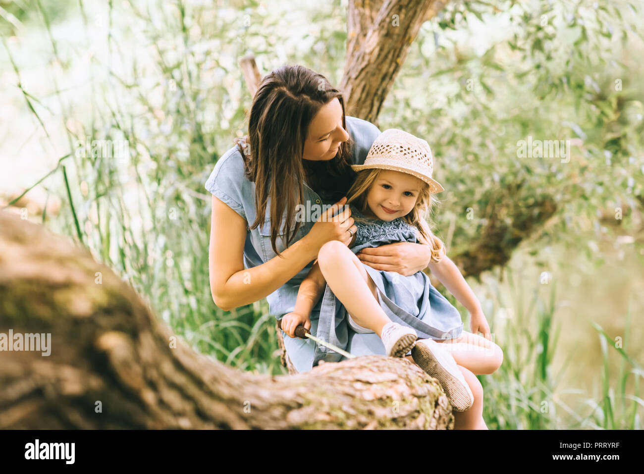 mother and adorable daughter hugging and sitting on tree trunk Stock ...