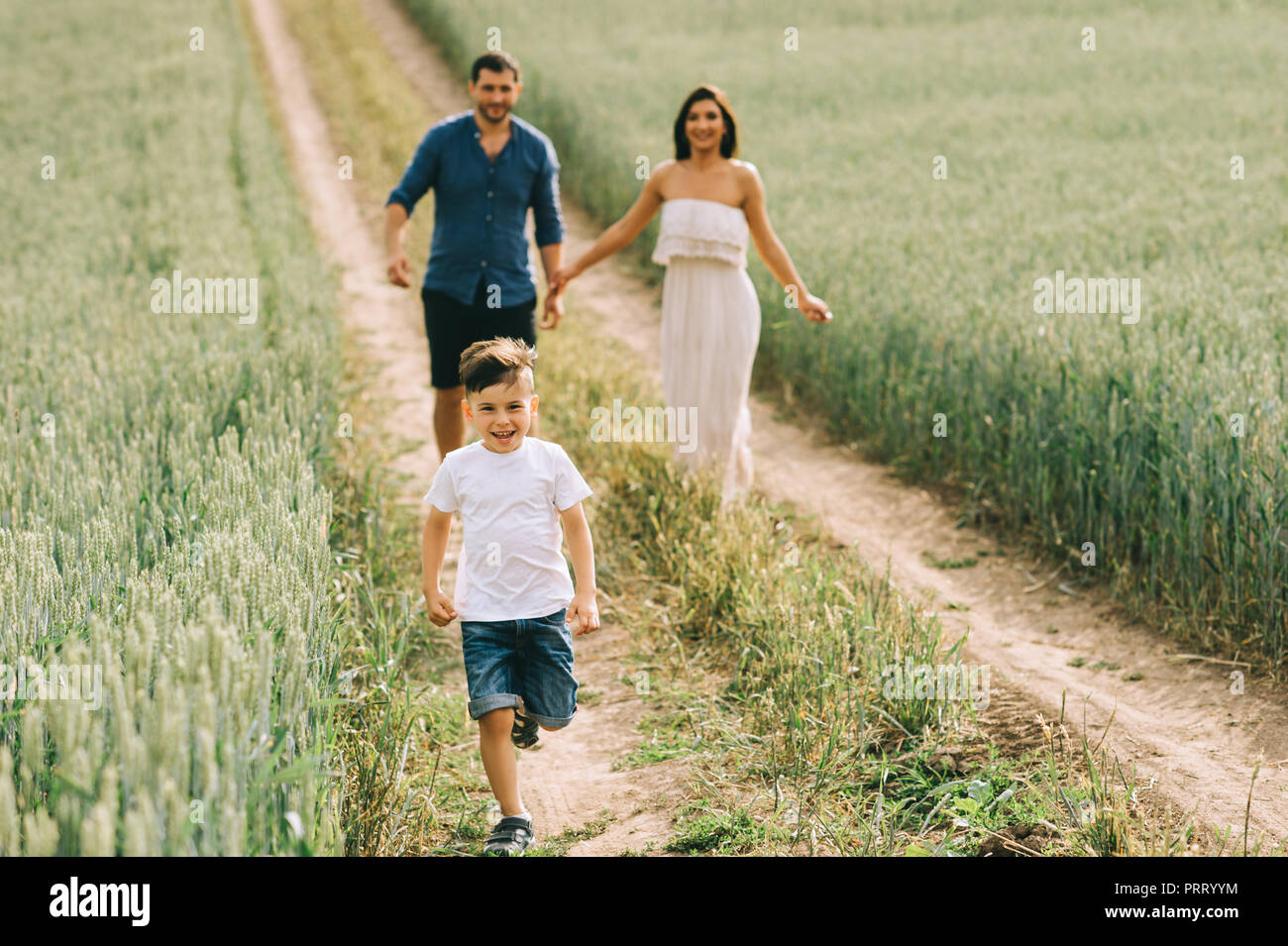 happy parents and son running on path in field Stock Photo - Alamy