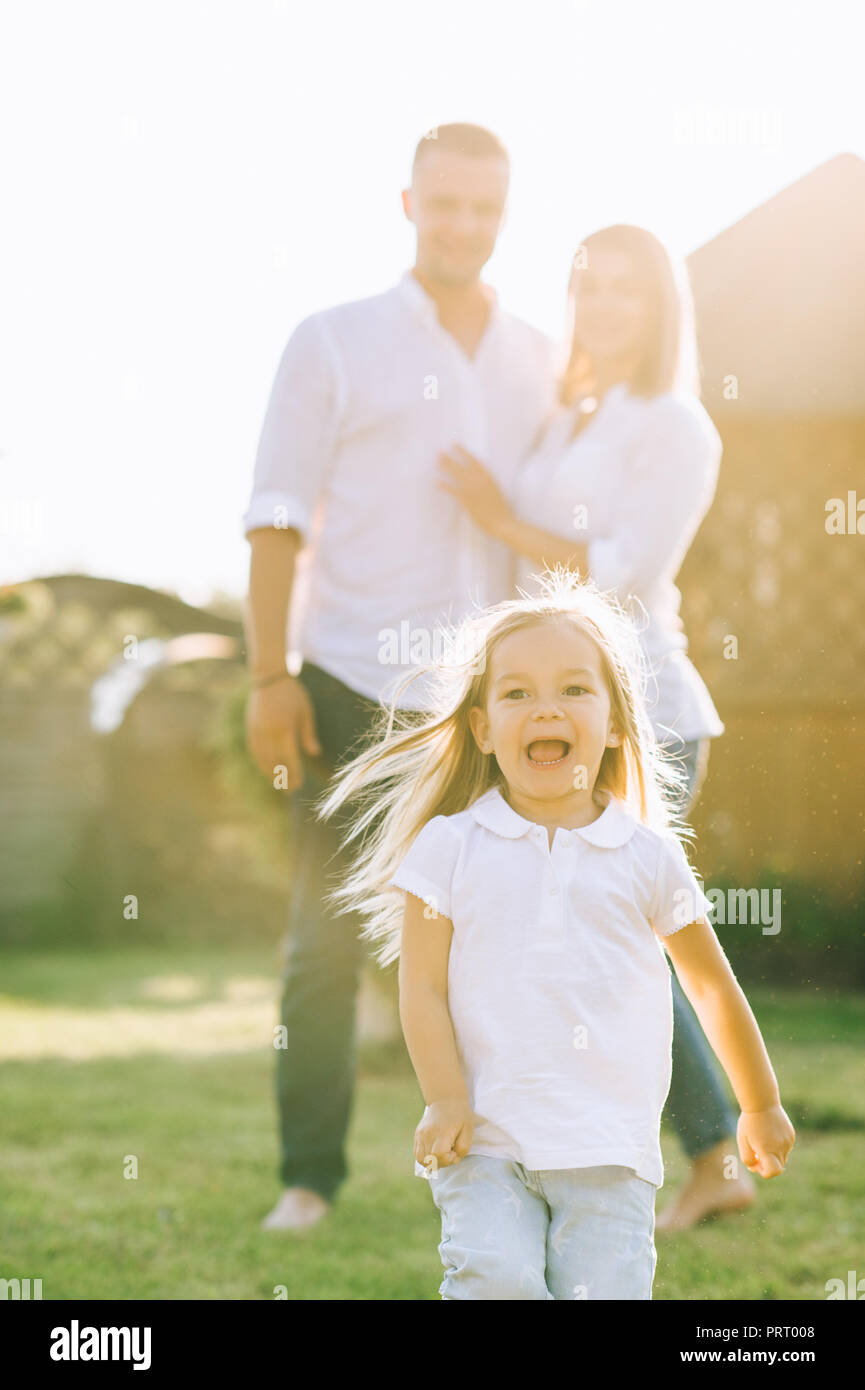 selective focus of little kid running while parents standing behind on ...
