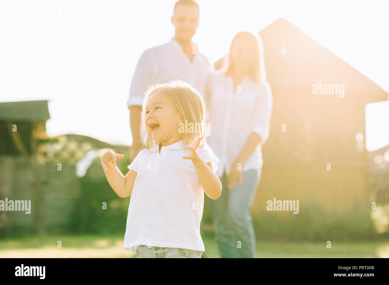 selective focus of happy little kid with parents behind on backyard ...