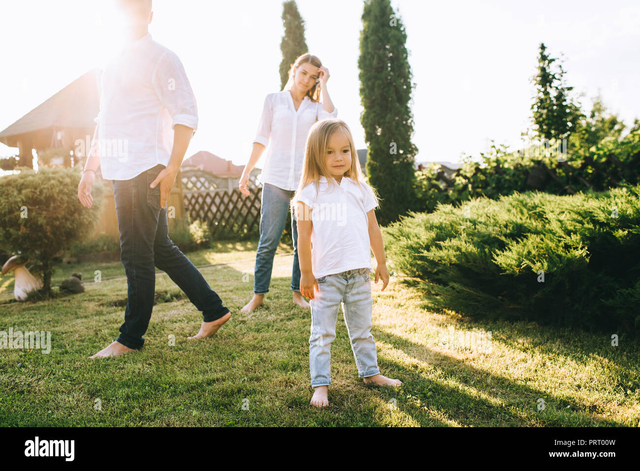 selective focus of little kid with parents behind on backyard Stock ...