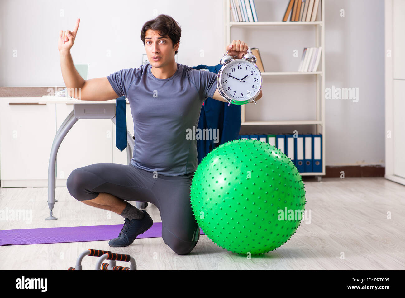 Young male employee exercising in the office Stock Photo - Alamy