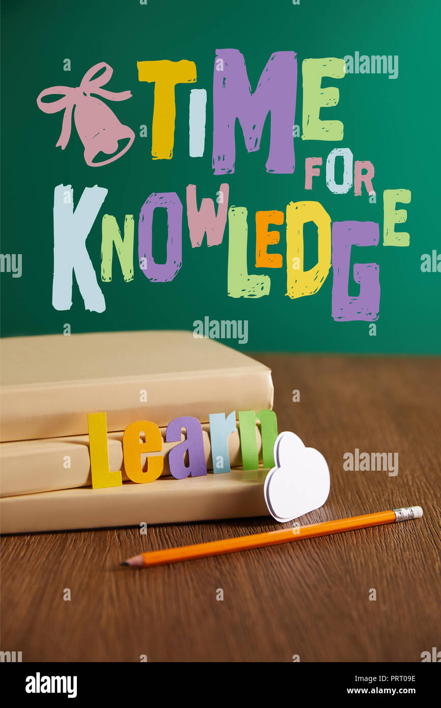 books, pencil, cloud sign and learn lettering on wooden table with ...