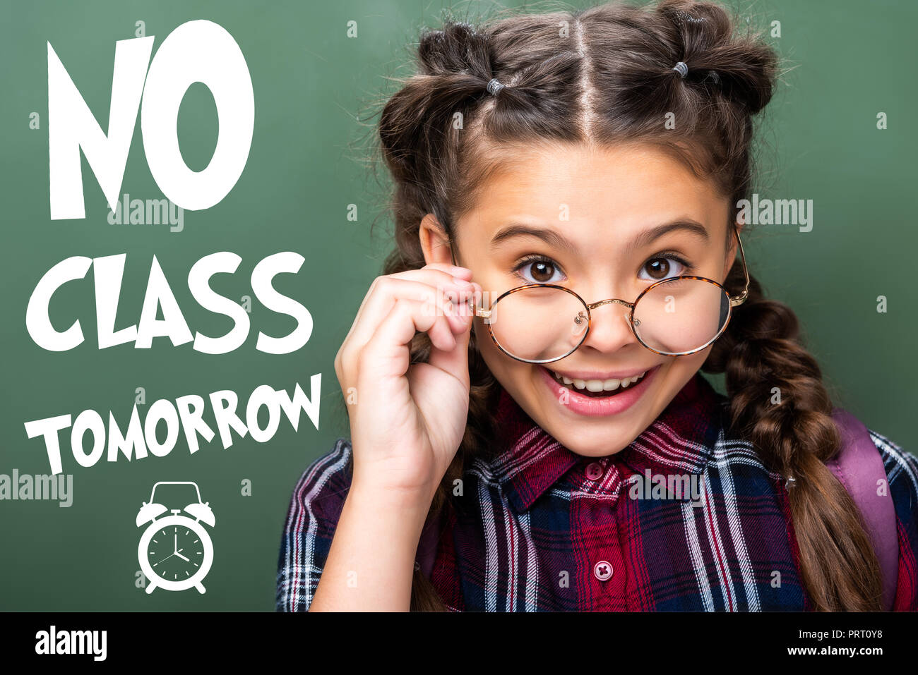 portrait of schoolchild looking above glasses near blackboard, with "no ...