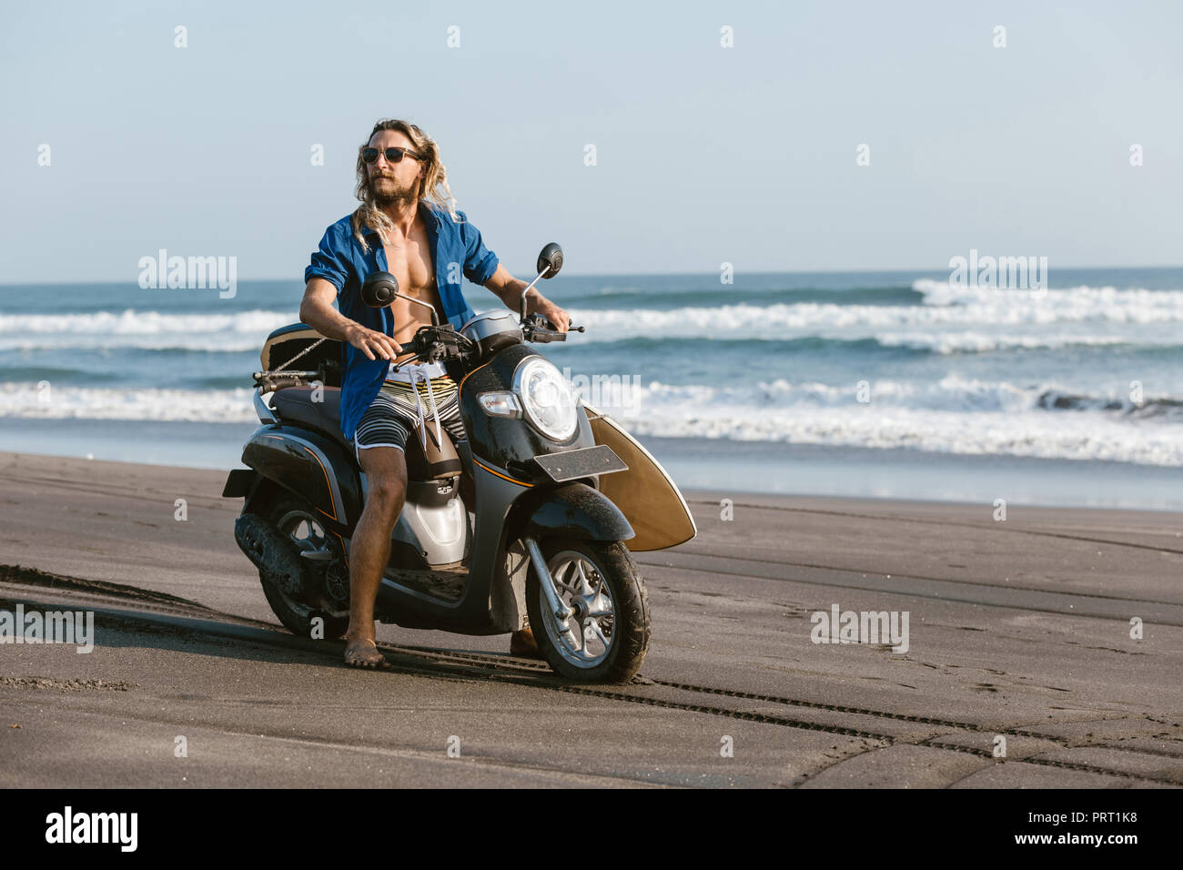 handsome biker sitting on scooter at beach in bali, indonesia Stock ...