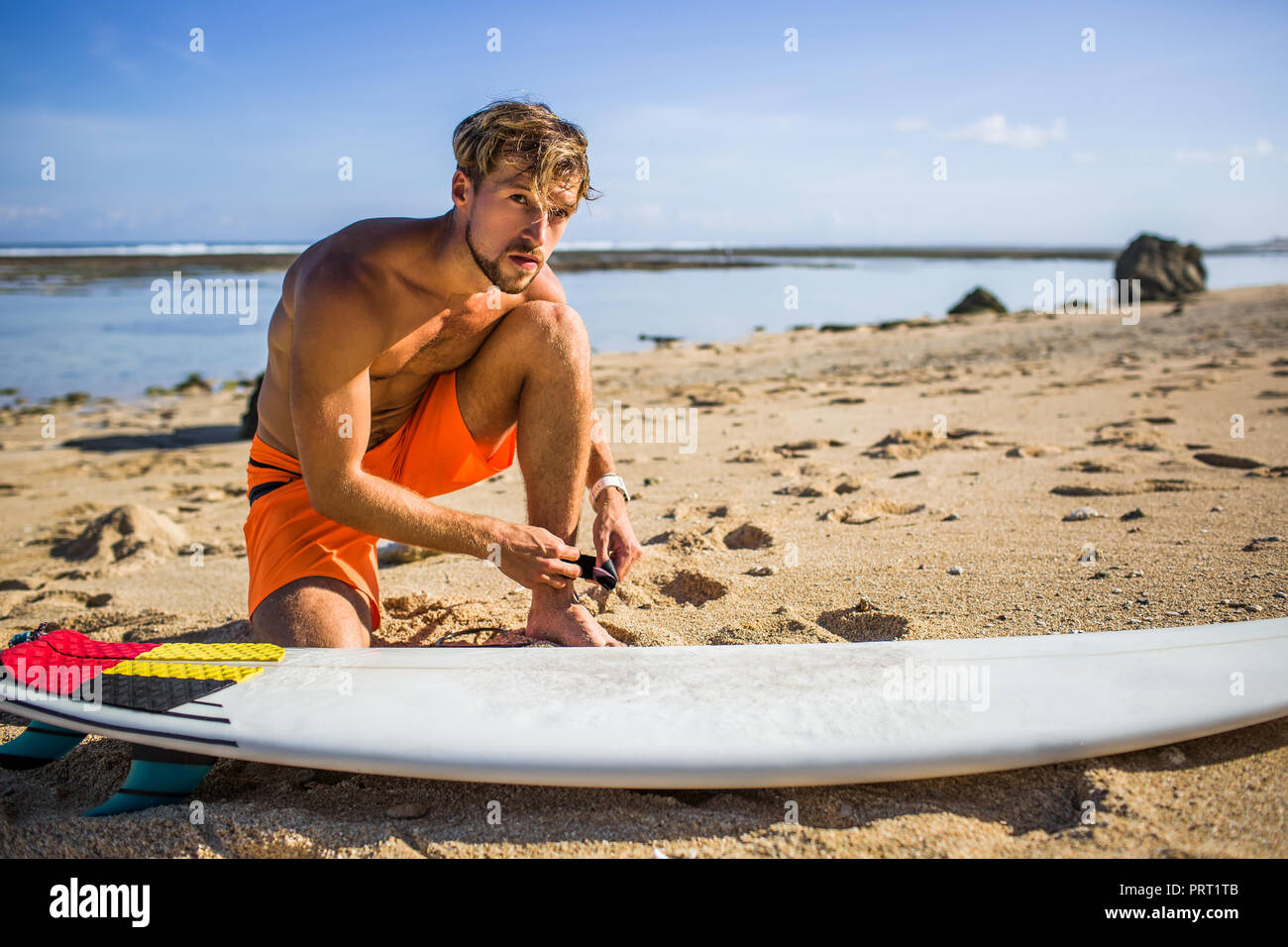 young sportsman getting ready for surfing on sandy beach Stock Photo ...