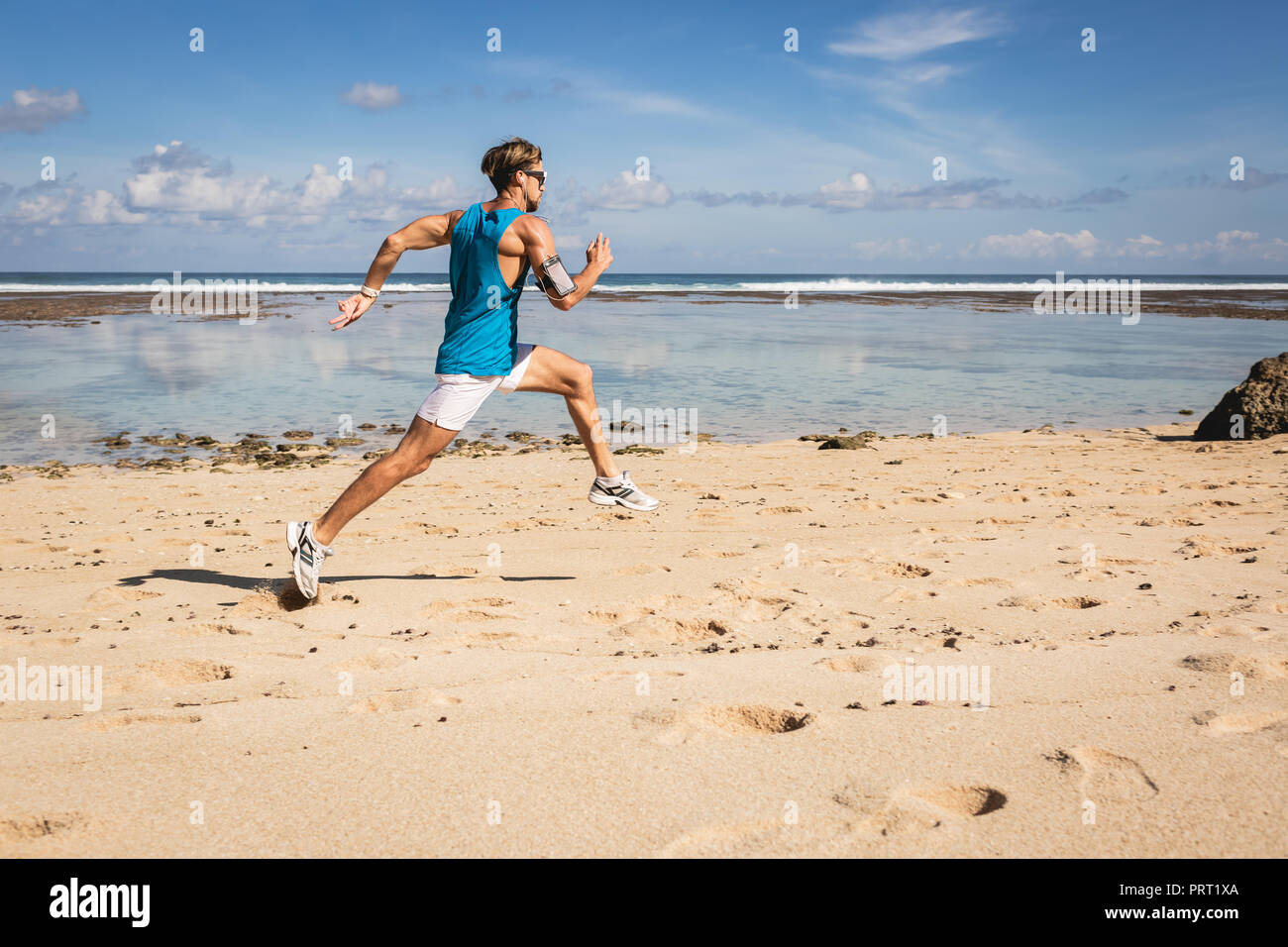 athletic man running and jumping on sand beach near sea, Bali ...