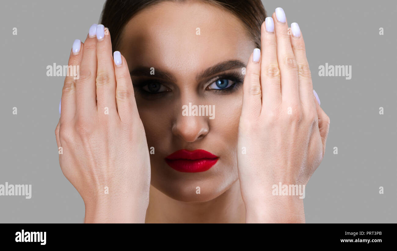Lady with strong face covering her face with her hands on gray ...