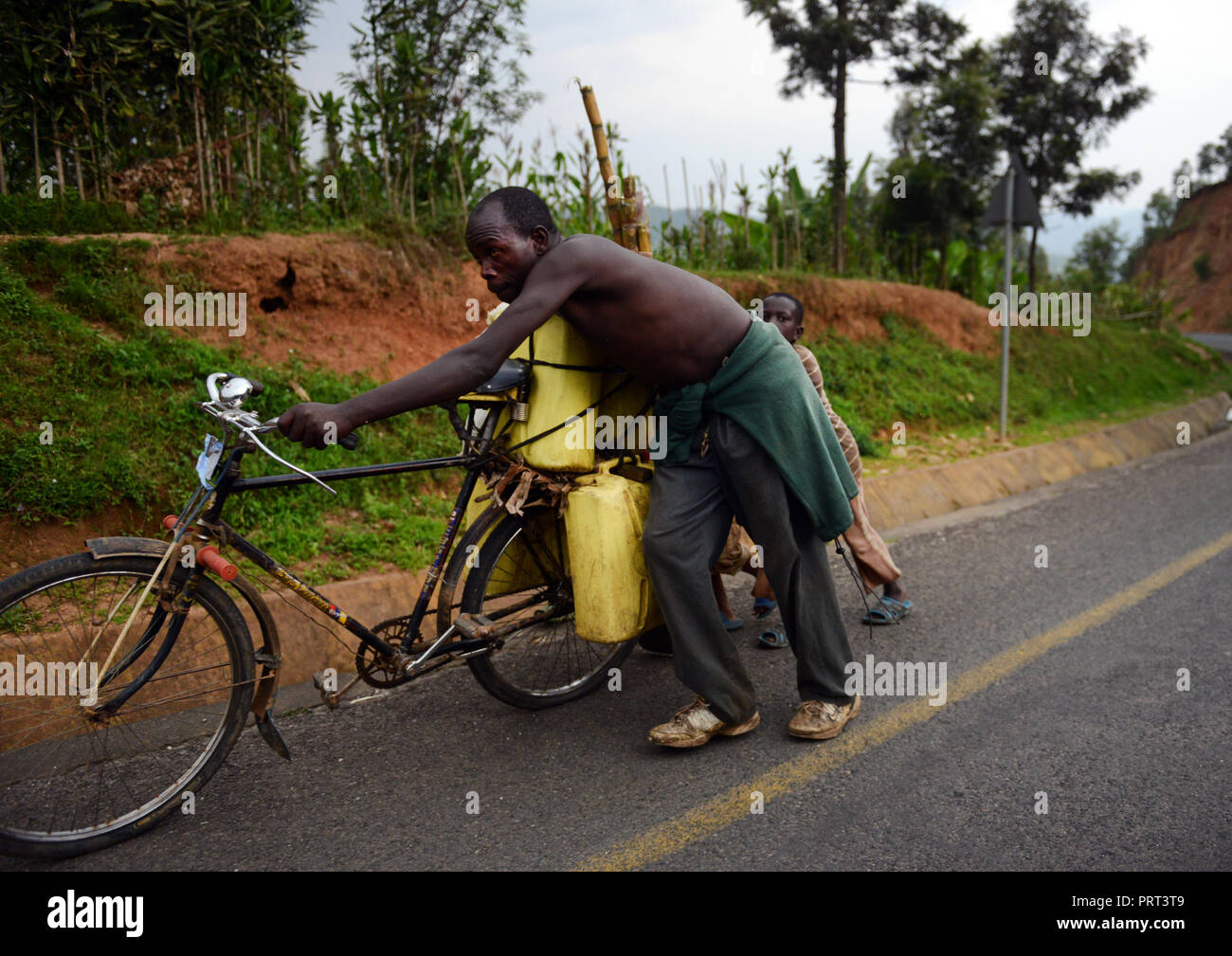 A Rwandan man pushing his bicycle up the hill Stock Photo - Alamy