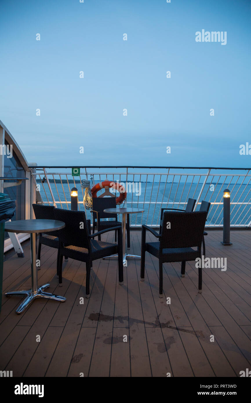 Empty deck on a car ferry with tables and chairs when it is still dark ...