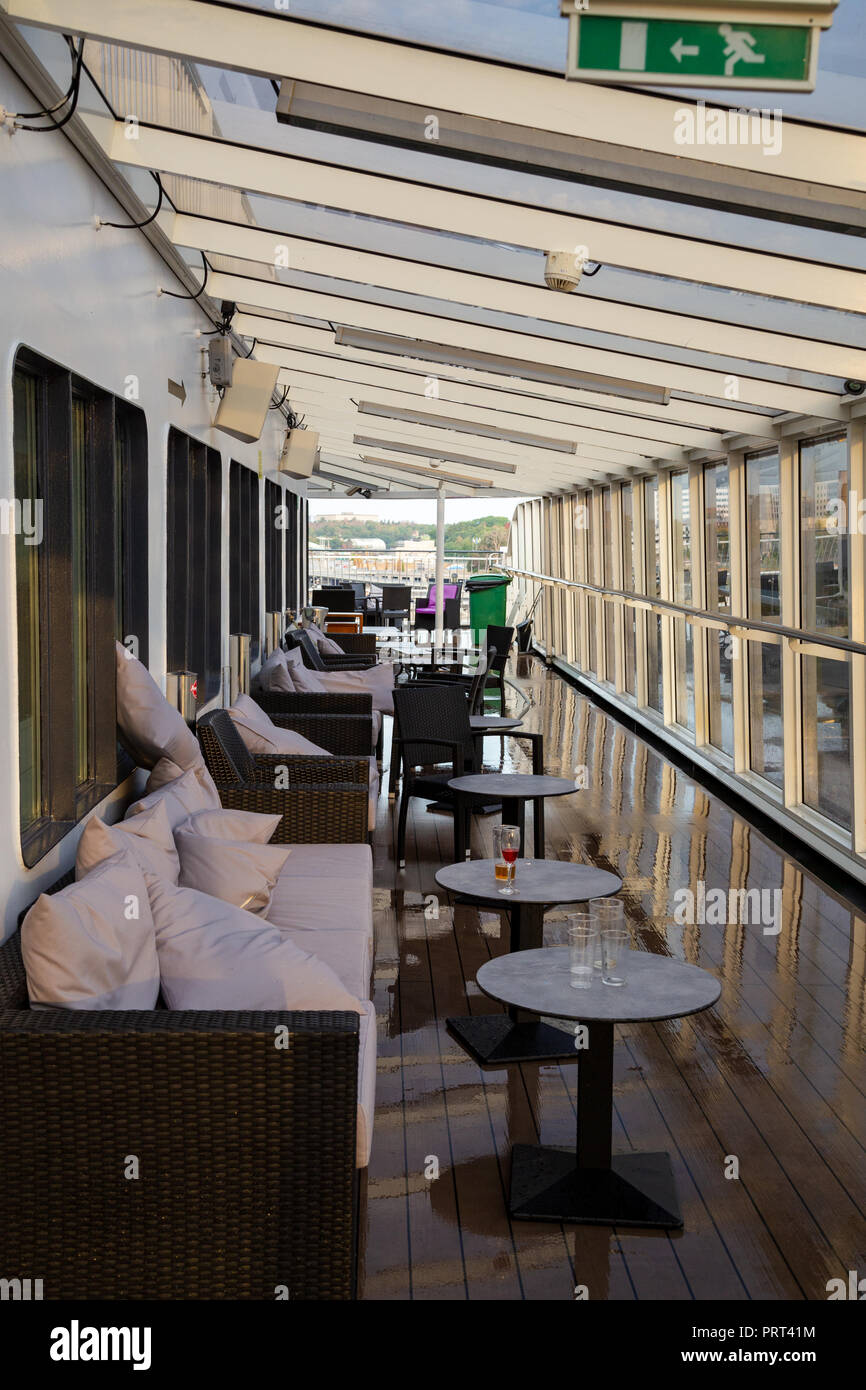 Messy deck on the morning on a ship with old glasses on the tables ...