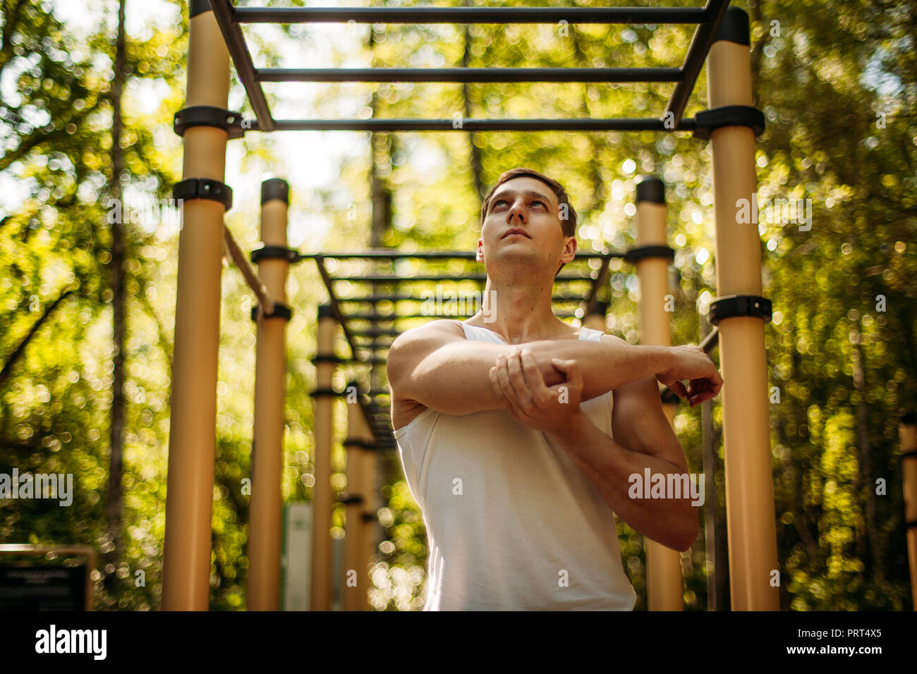 Handsome man warming up before street workout. Middle shot. Outside ...