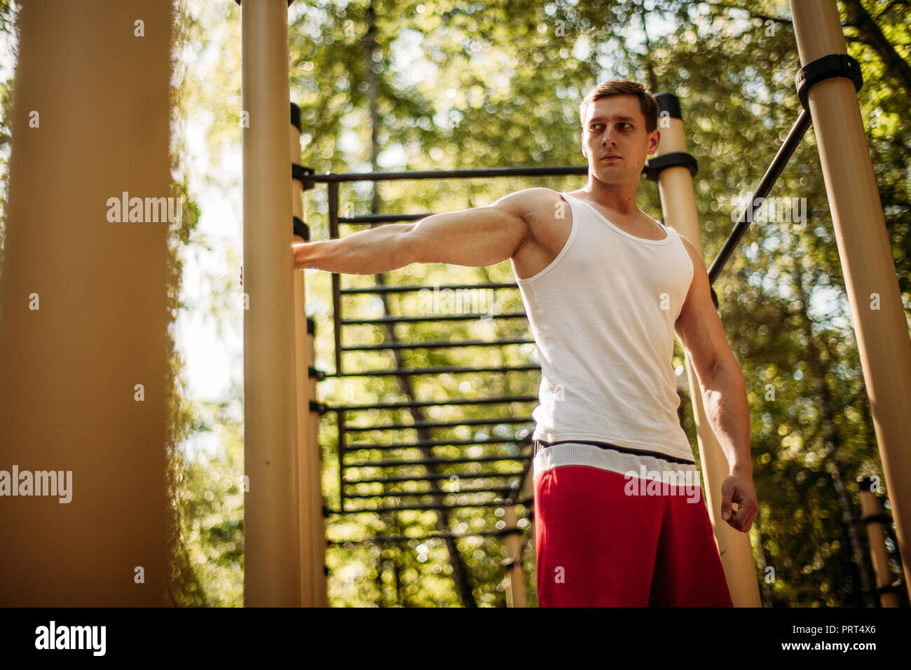 Handsome man warming up before street workout. Middle shot. Outside ...