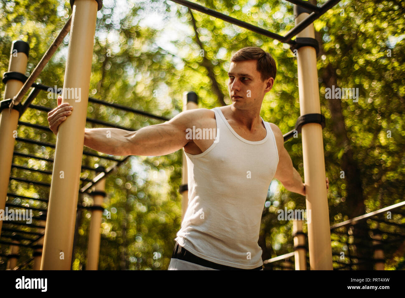Handsome man warming up before street workout. Middle shot. Outside ...