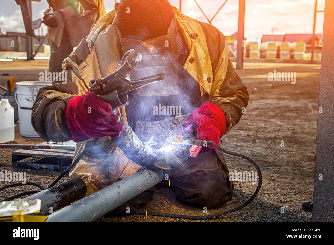 A strong man is a welder in brown uniform, welding mask and welders ...