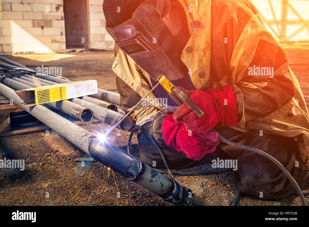 A strong man is a welder in brown uniform, welding mask and welders ...