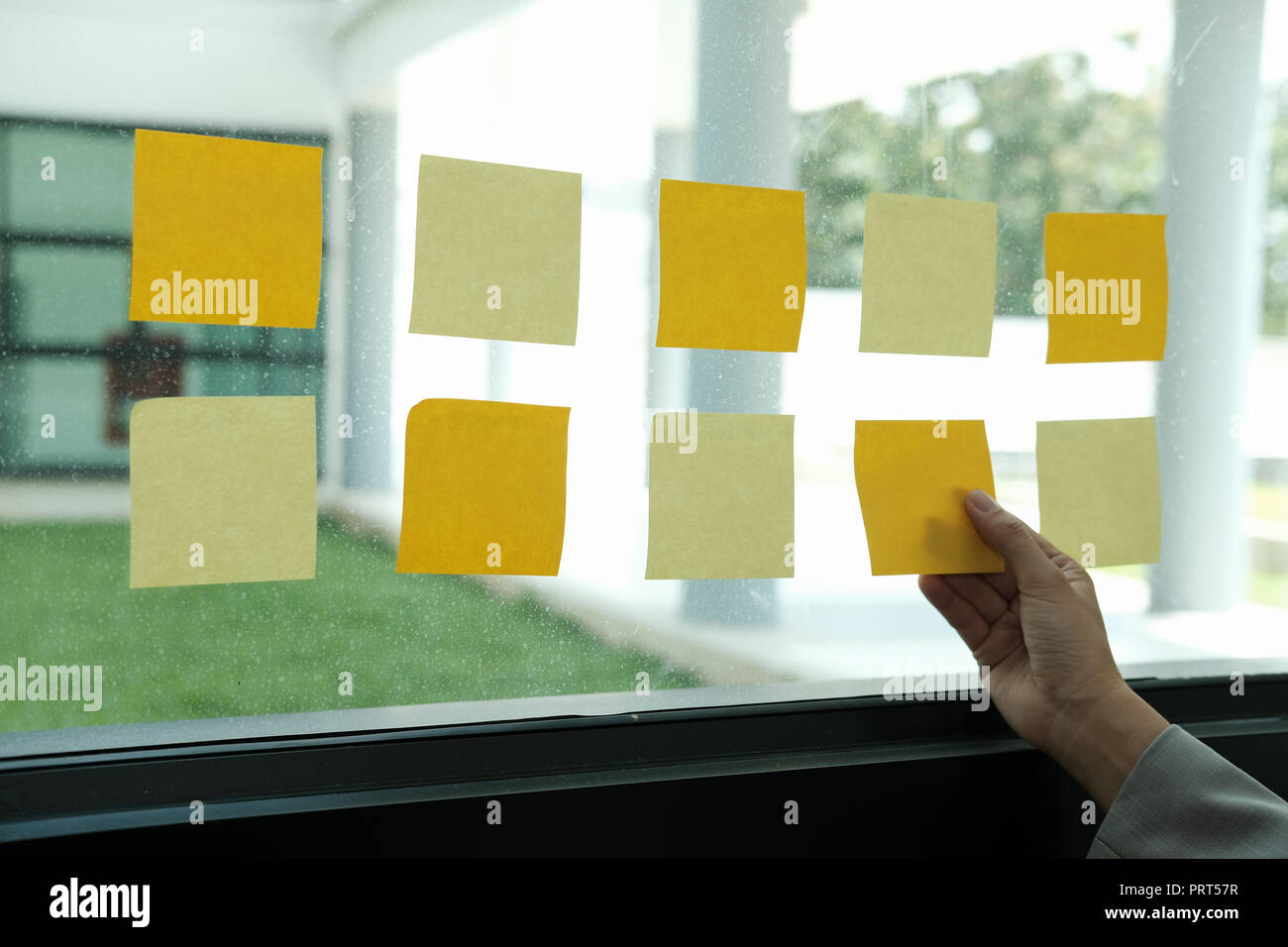 hand hold adhesive notes on glass wall at workplace. Sticky note paper ...