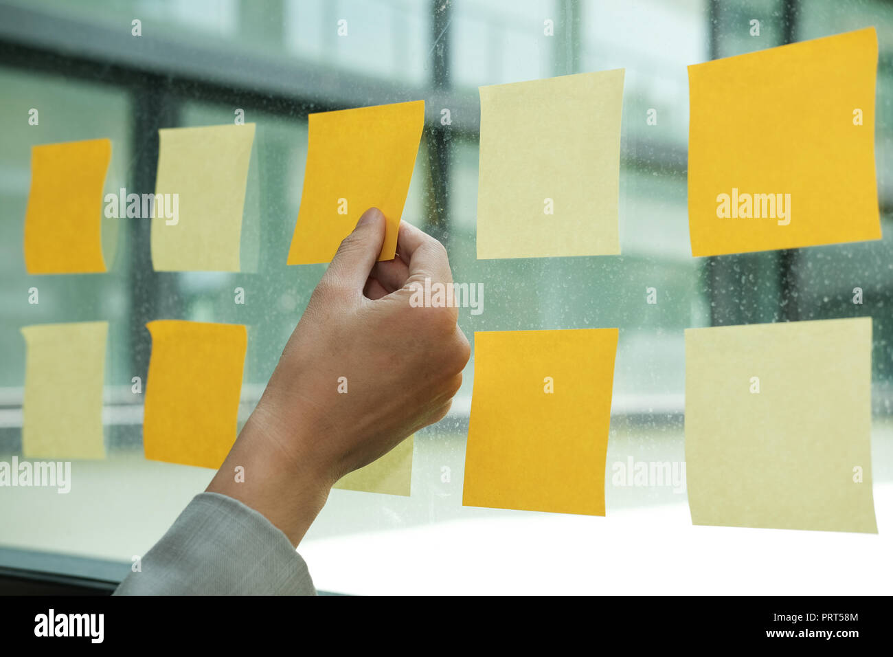 hand hold adhesive notes on glass wall at workplace. Sticky note paper ...