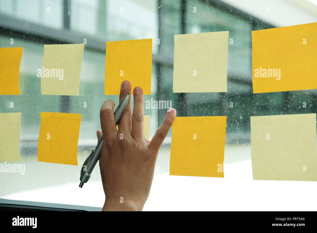 hand touch on adhesive notes on glass wall at workplace. Sticky note ...