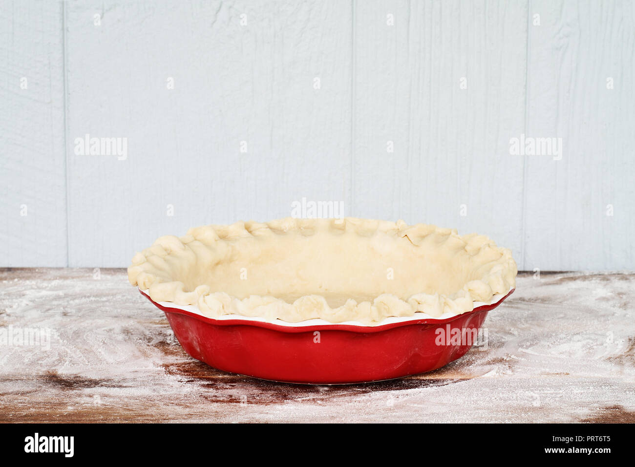 Homemade butter pie crust in pie plate with fluted pinched edge against ...