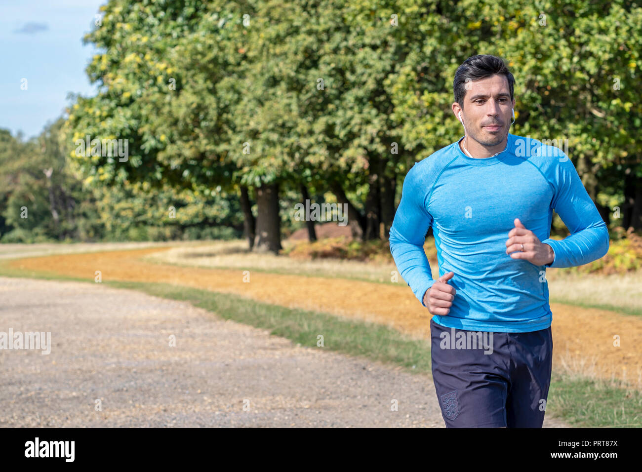 Attractive Man Jogging in the Park. Personal Trainer running and doing ...