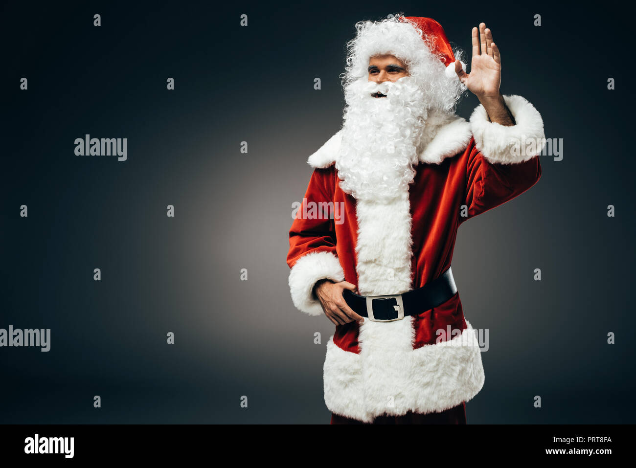 happy santa claus in costume waving by hand isolated on grey background ...