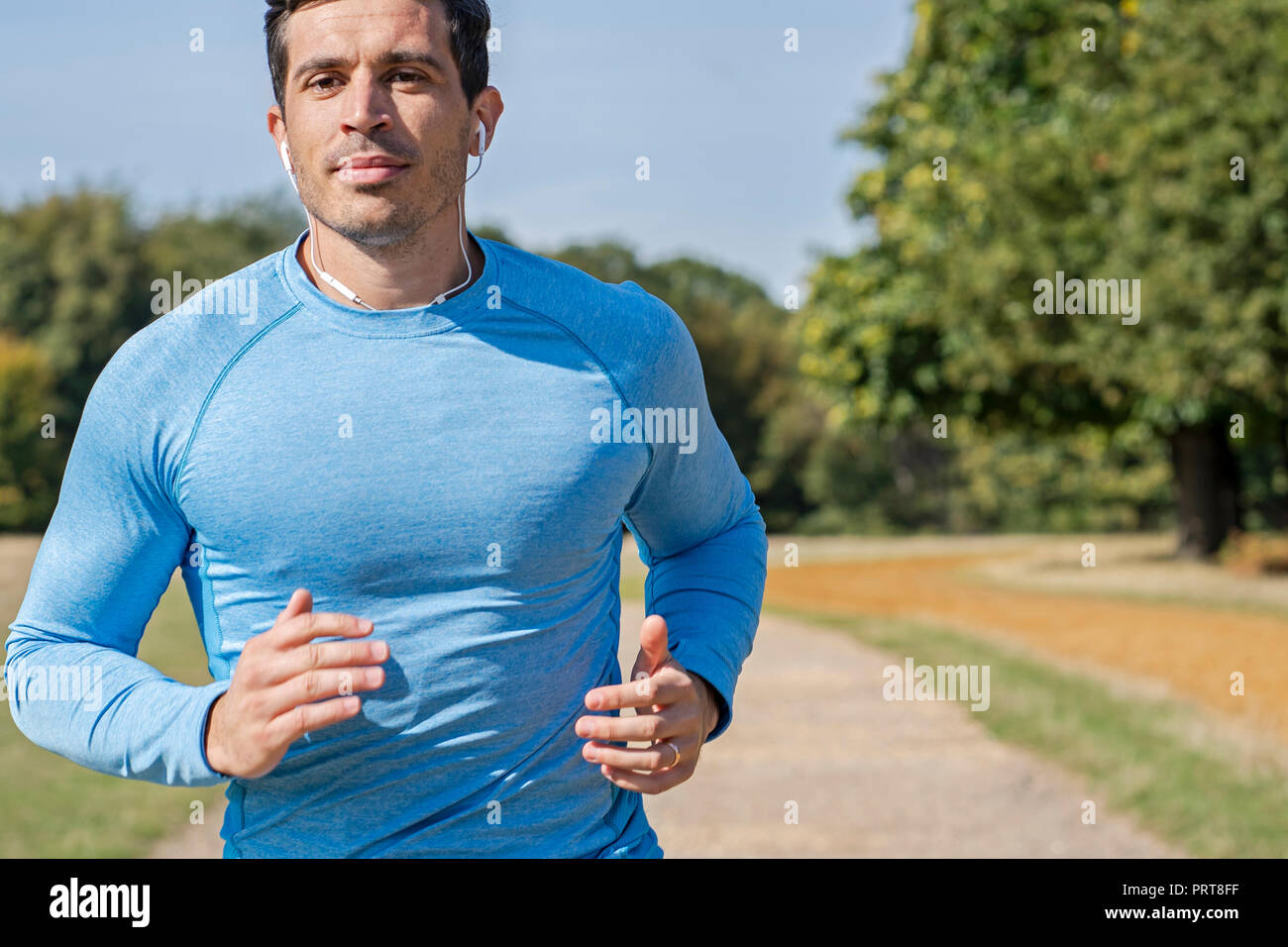 Attractive Man Jogging in the Park. Personal Trainer running and doing ...