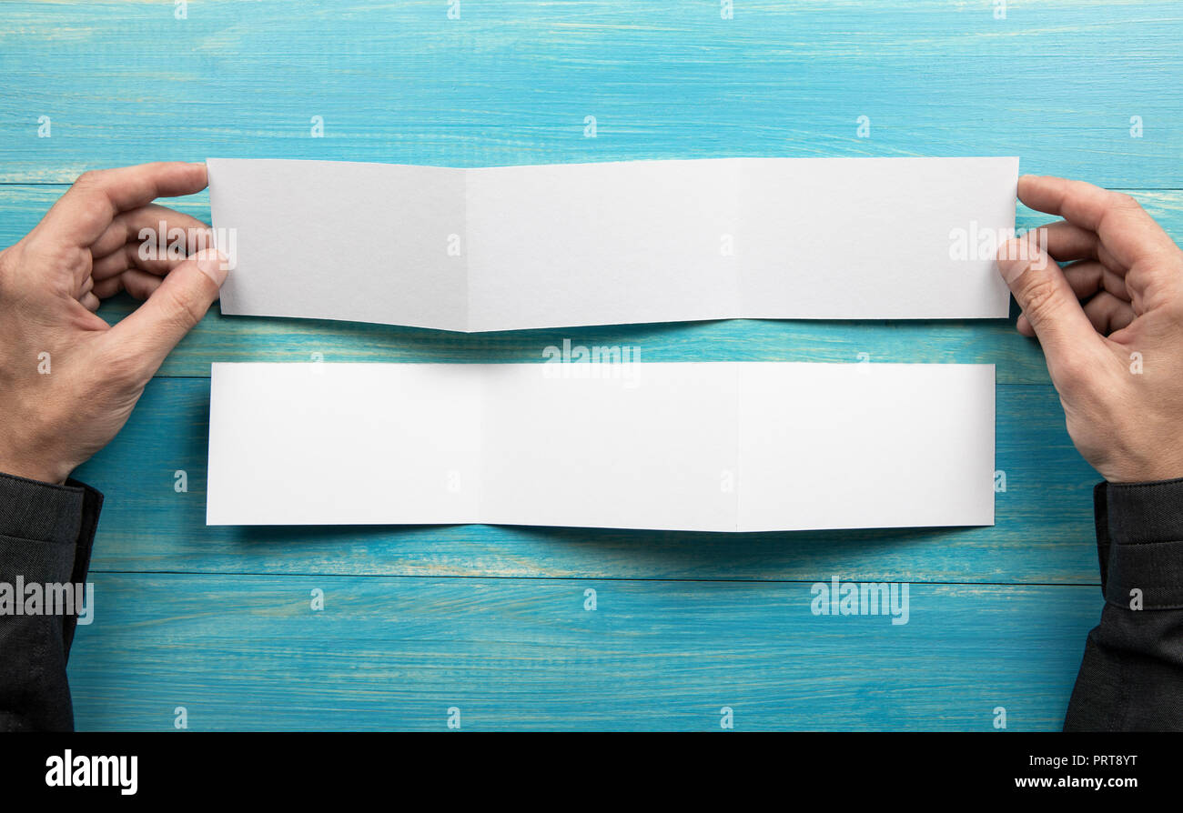 Mens hands holding empty white booklet on blue wooden background. View ...