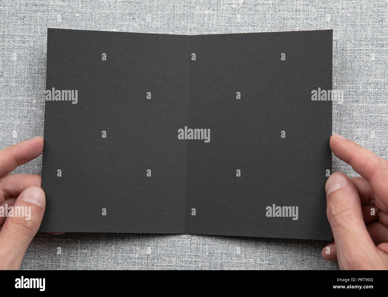 Mens hands holding empty black booklet on gray background. View from ...