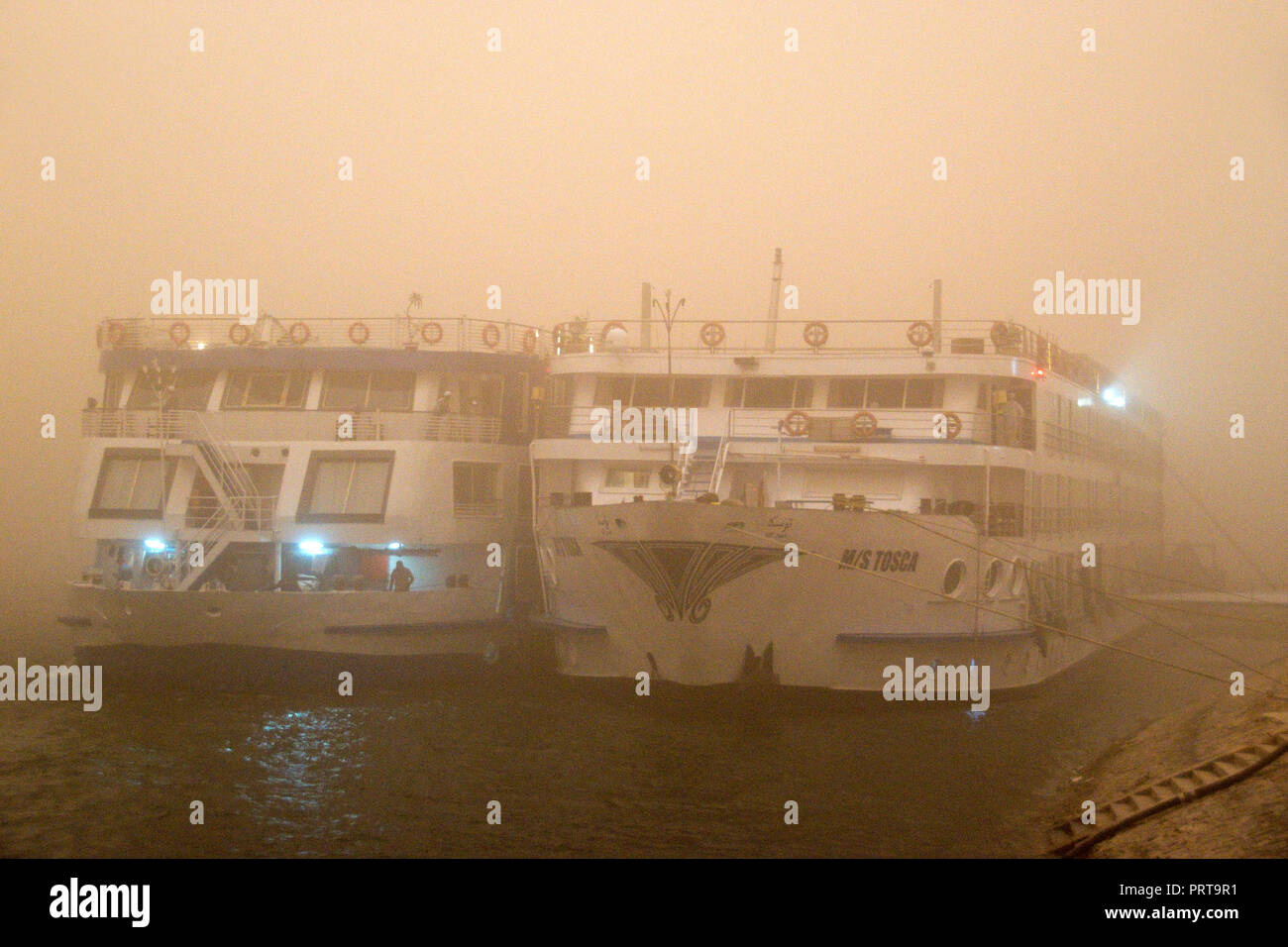 Nile river cruise ships moored in the Nile during an evening sandstorm ...