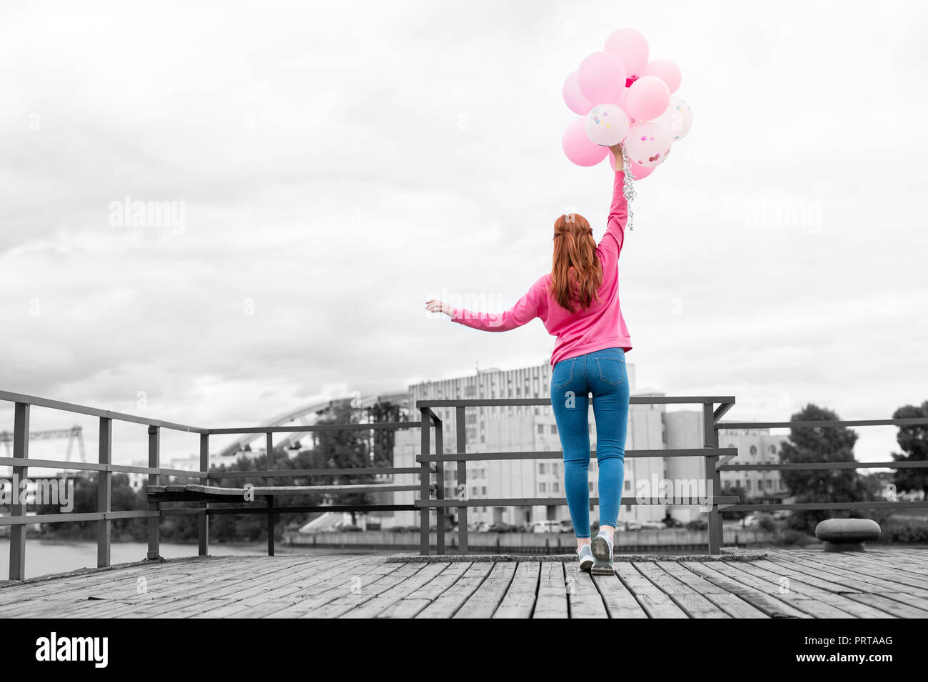 Young girl stretching herself up while holding pink balloons Stock ...