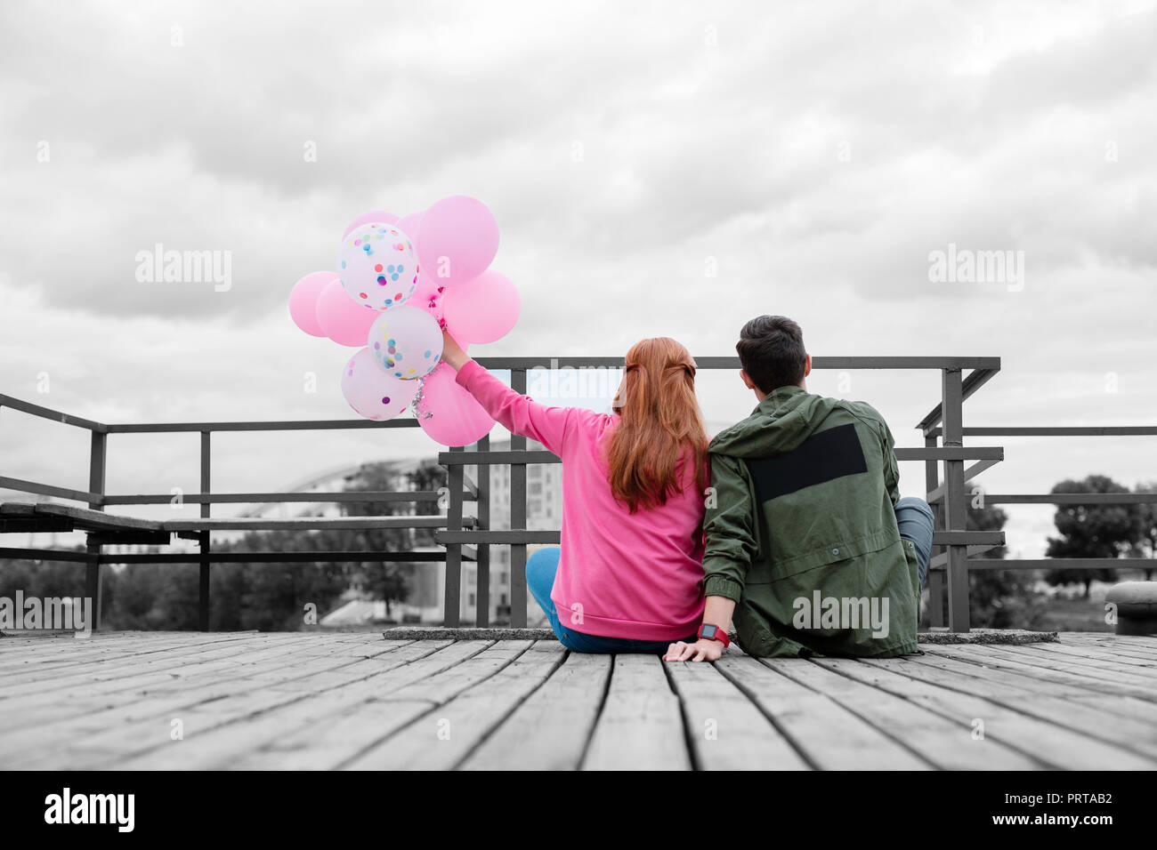 Two people sitting on the pier close to each other Stock Photo - Alamy