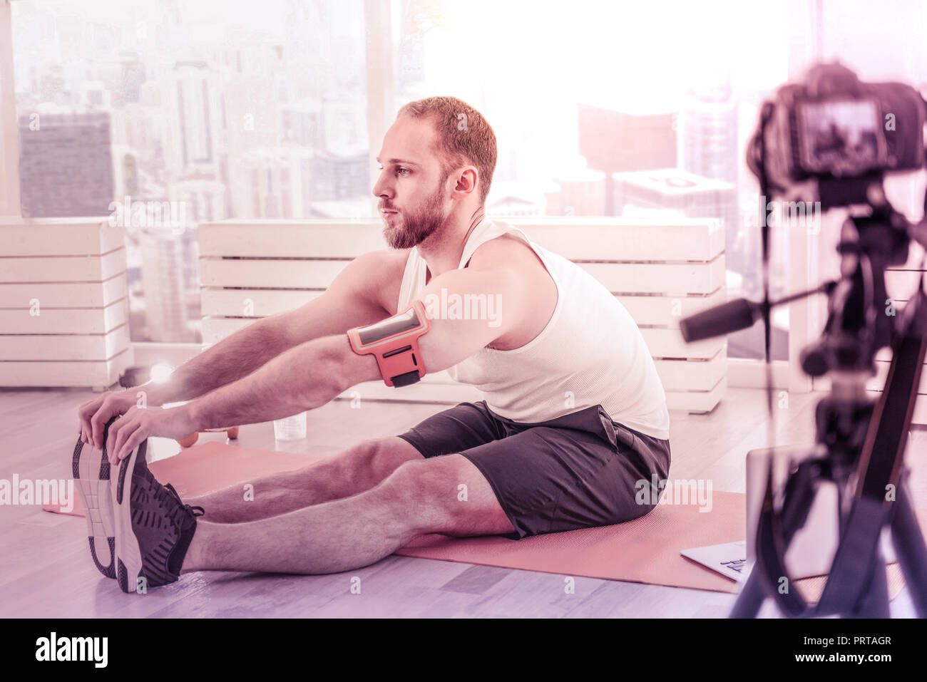 Profile of concentrated athlete doing stretching exercises on the floor ...