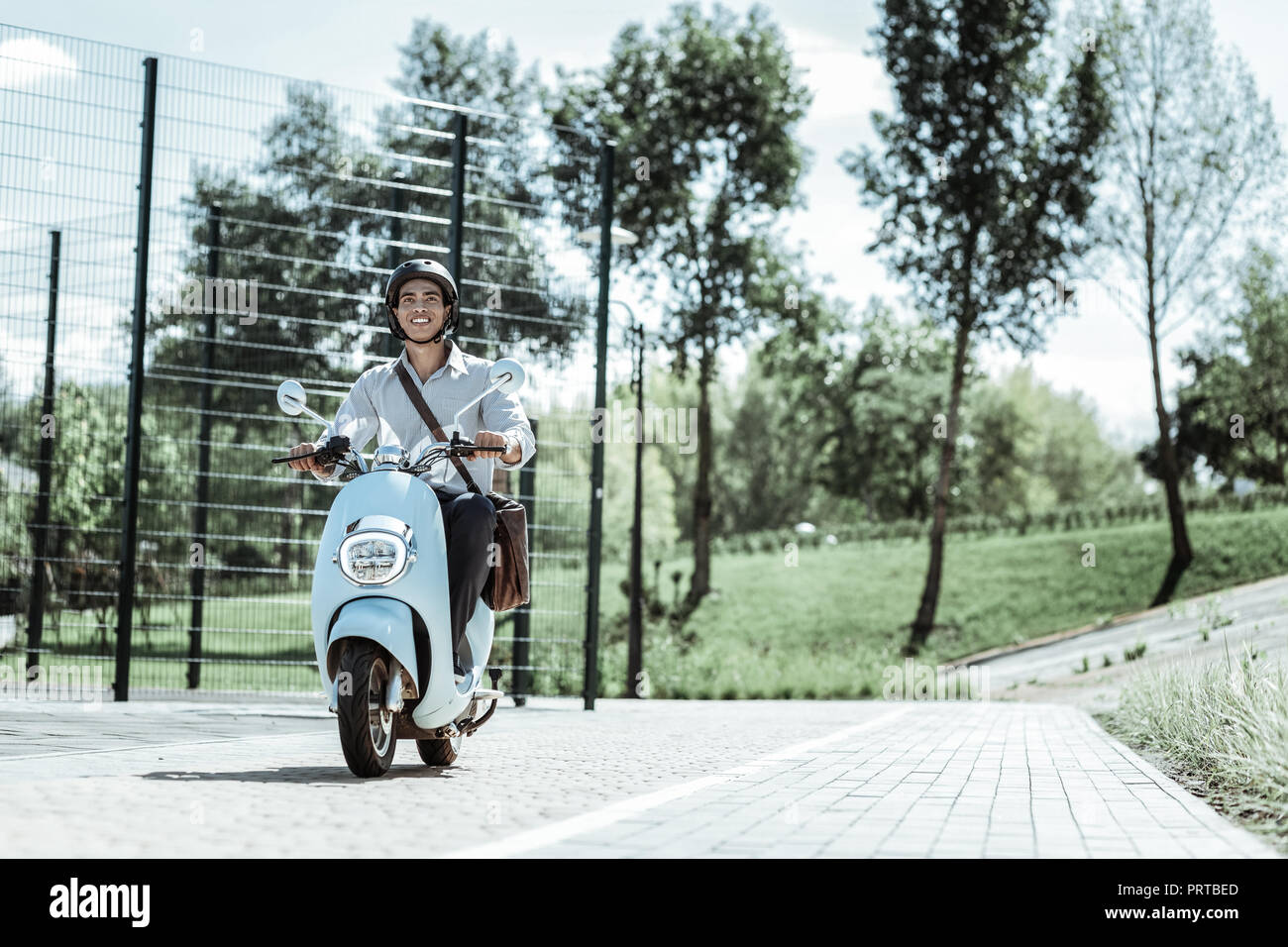 Merry male student riding to university on motorbike Stock Photo - Alamy
