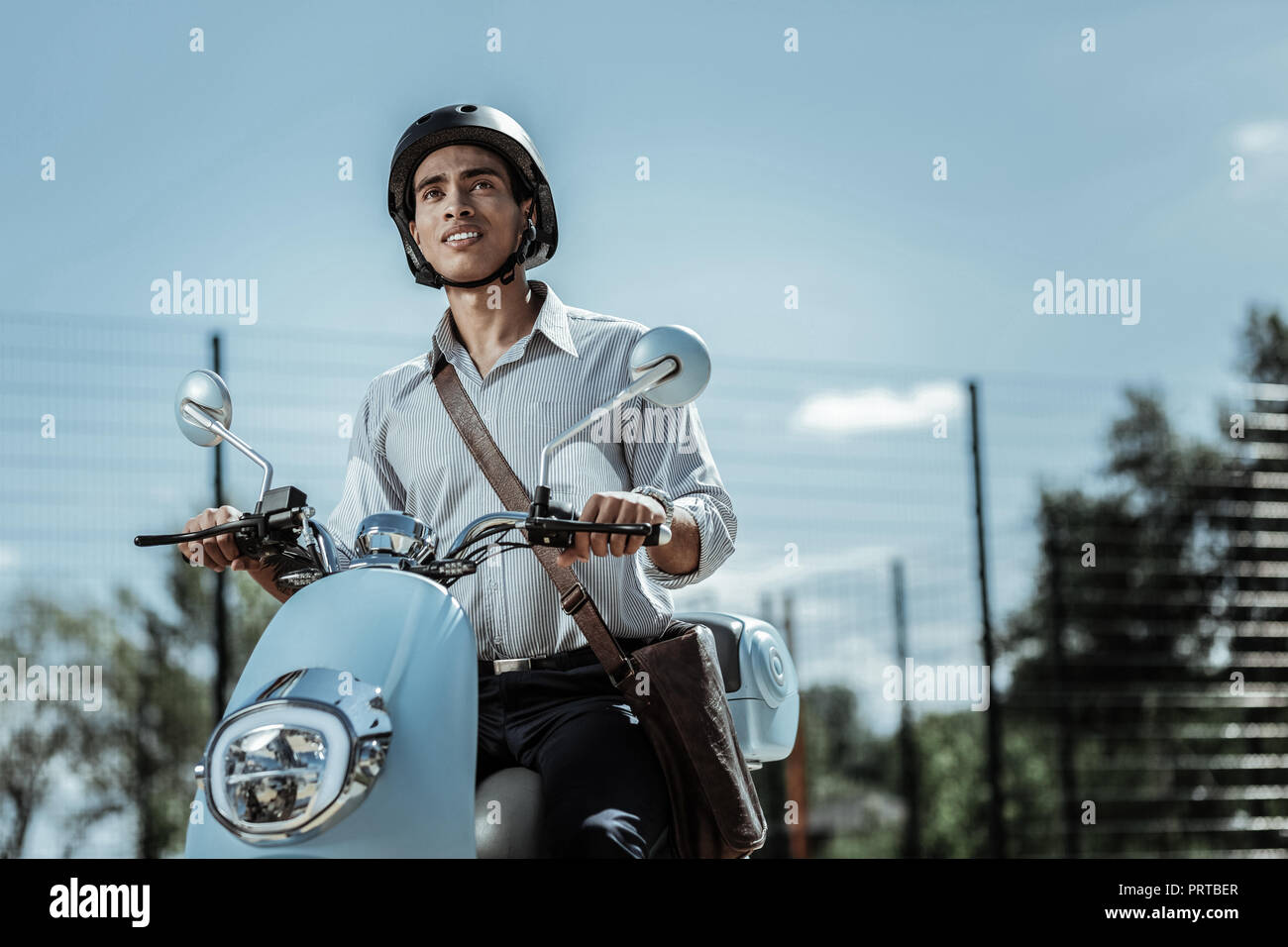 Positive male student taking ride on motorbike Stock Photo - Alamy