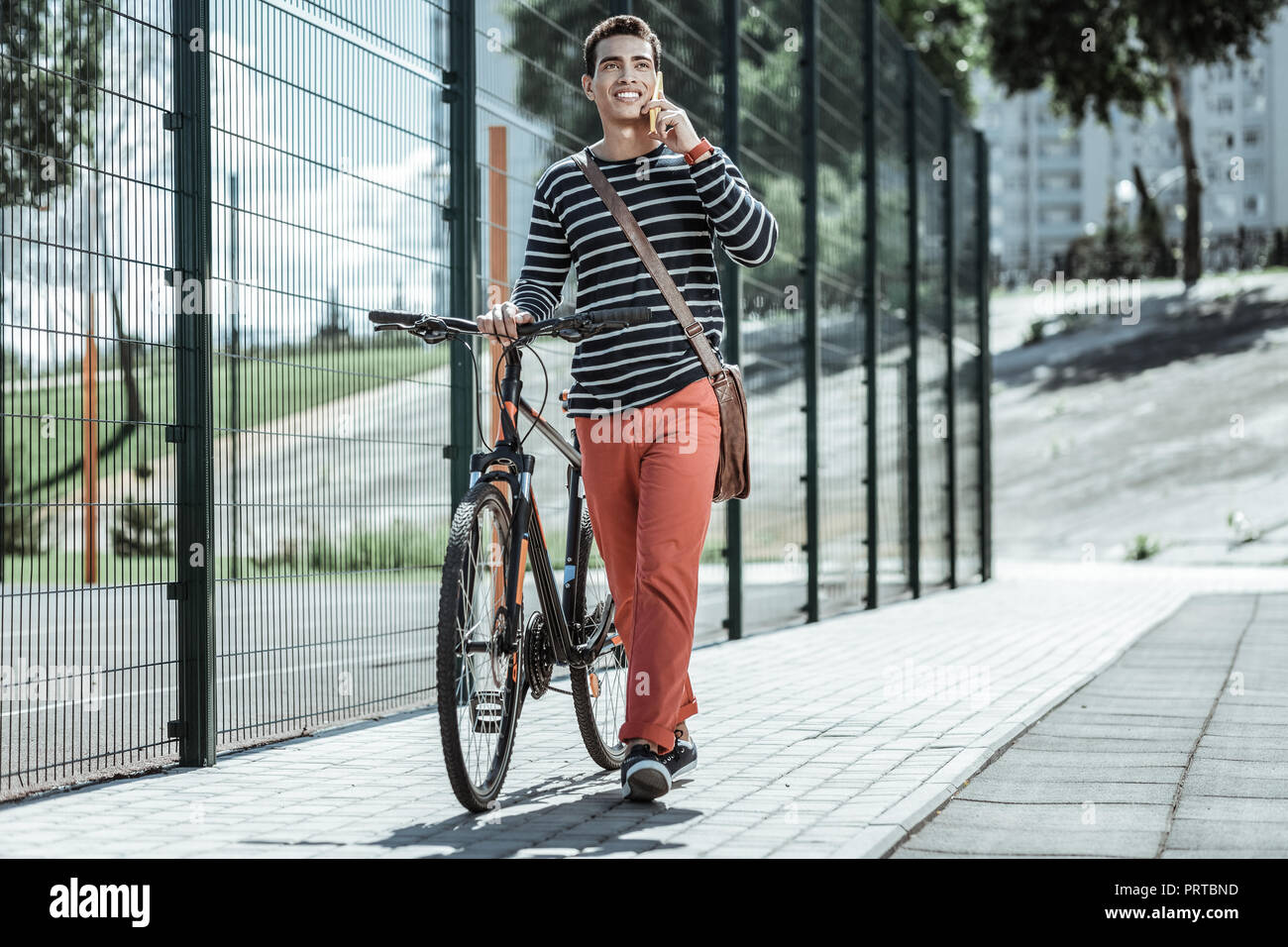 Cheerful positive guy approaching destination on bicycle Stock Photo ...