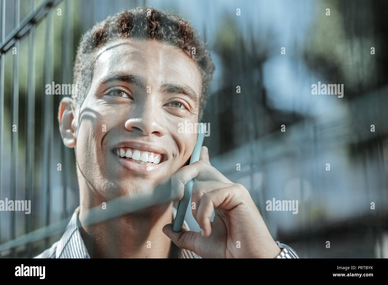 Optimistic pretty guy talking over plans on smartphone Stock Photo - Alamy