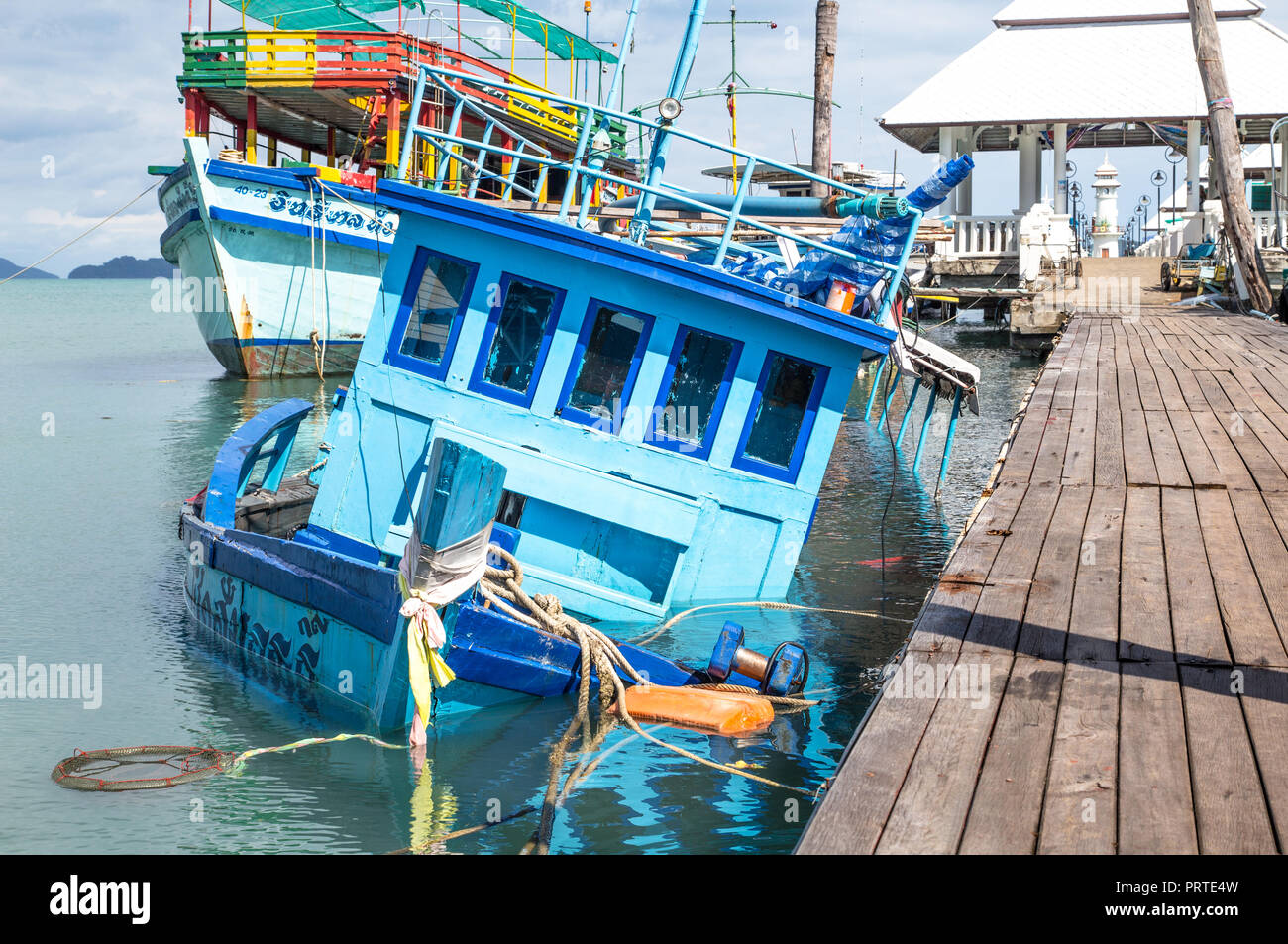 sunken fishing boat near the pier, partly submerged in the water Stock ...