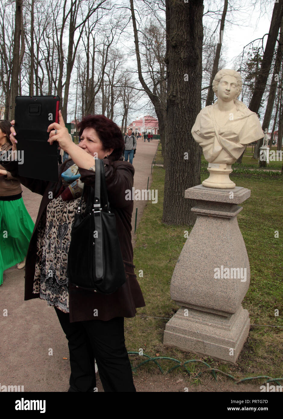 A woman takes a photograph of herself, with a statue, on her laptop ...
