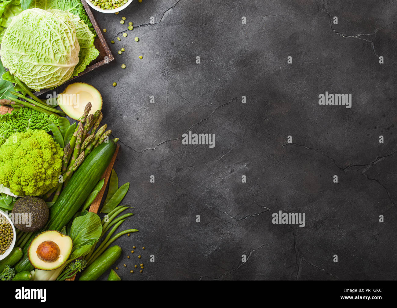 Assorted green toned raw organic vegetables on dark background. Avocado ...