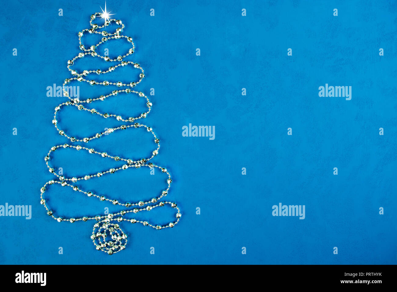 Christmas decoration tree of silver shine garland over blue background ...